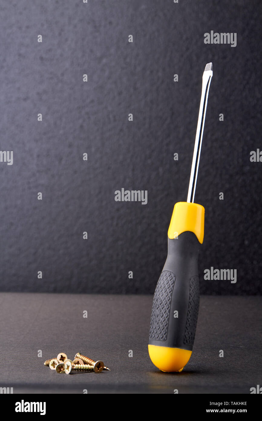 Screwdriver and screws on dark background. Tools for construction or ...