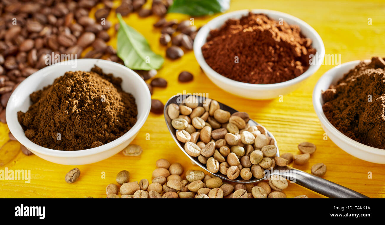 Raw white coffee beans with assorted roasted freshly ground coffee in ...