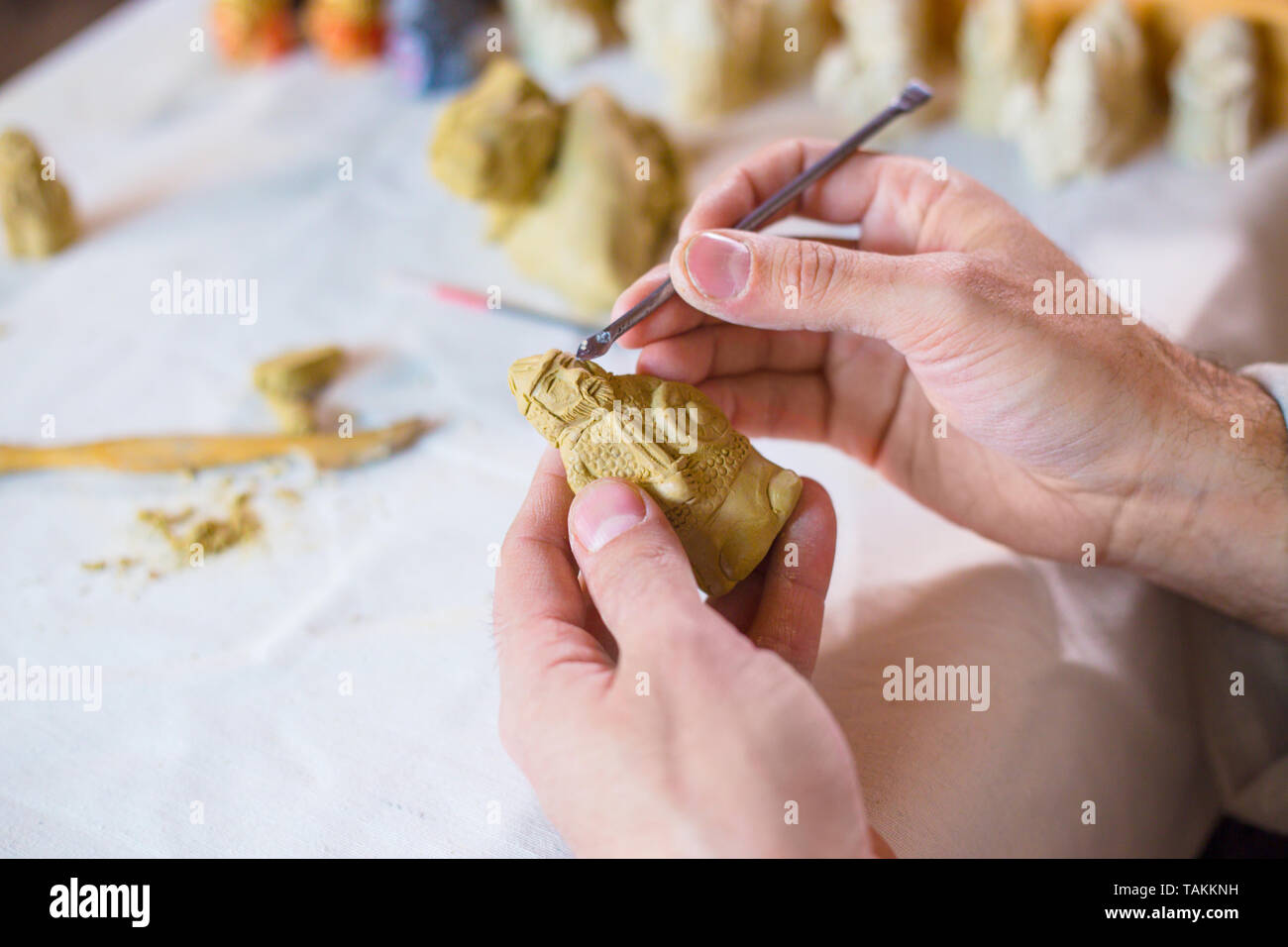 Professional male potter making clay figure for medieval popular ...