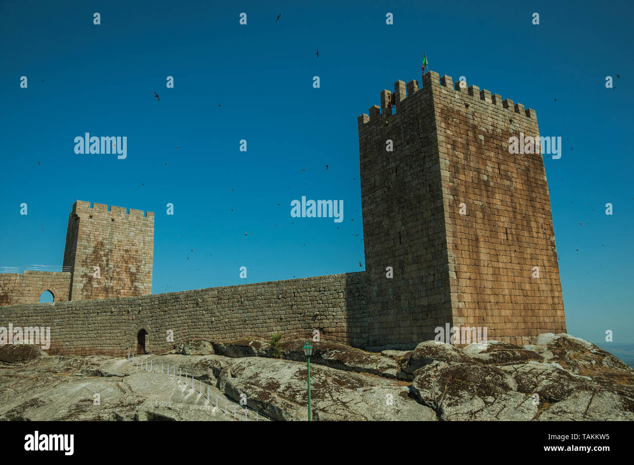 Stone wall with gateway and towers over rocky hill at the Linhares da ...