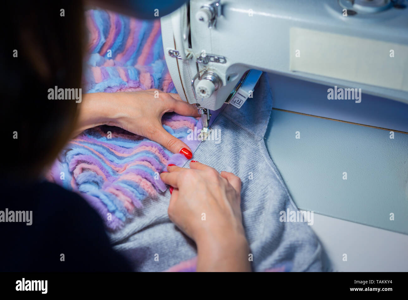 Close up shot - professional tailor, fashion designer sewing colorful ...