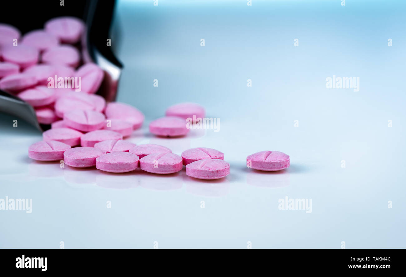 Pink tablets pills on blurred background of drug tray. Pharmaceutical ...