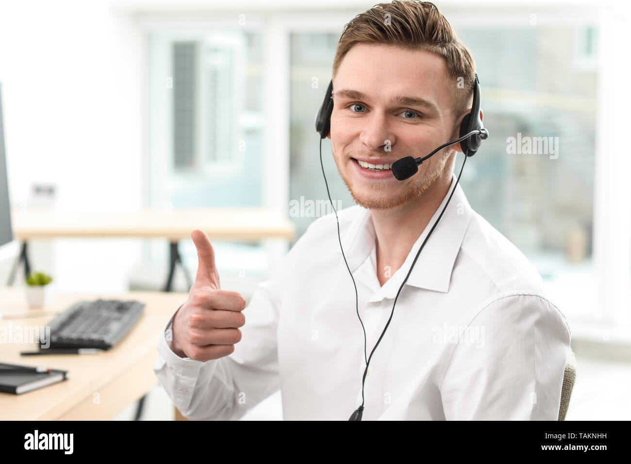 Portrait of male technical support agent showing thumb-up in office ...