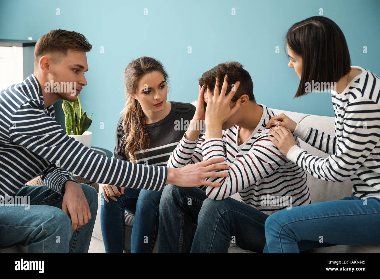 Group of people calming their friend indoors Stock Photo - Alamy