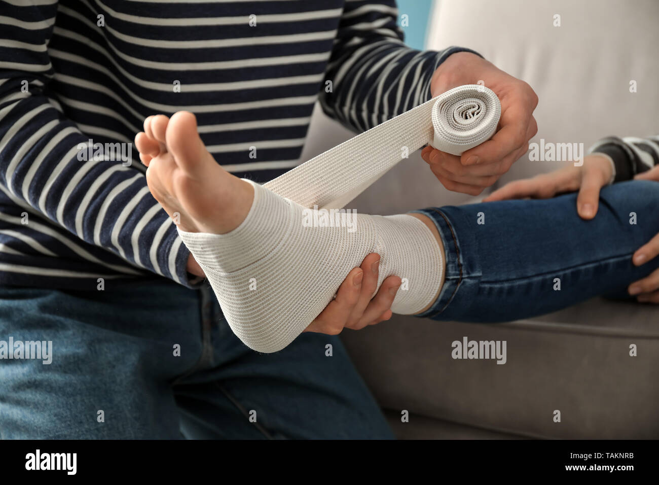 Man applying bandage onto his wife's leg at home Stock Photo - Alamy