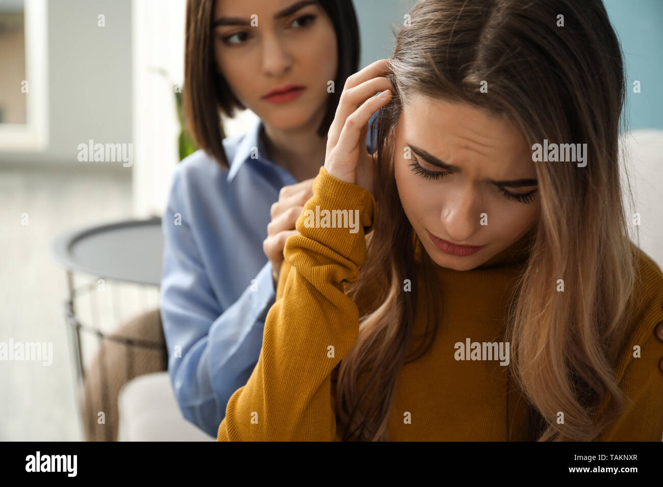 Young woman calming her friend indoors Stock Photo - Alamy