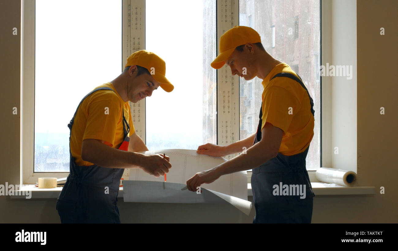 Construction workers looking at blueprint. Two young builders ...