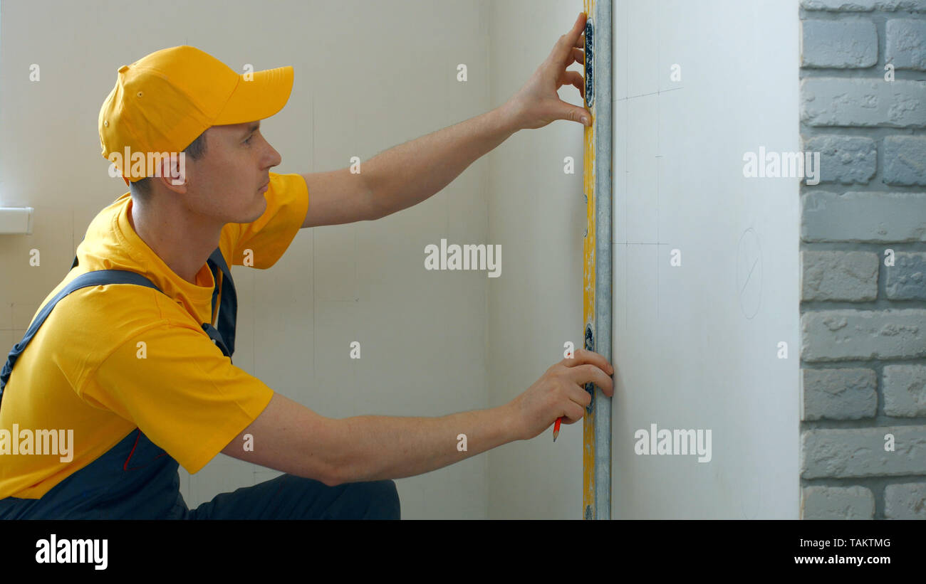 Repairman making measurement of wall. Young caucasian builder measuring ...