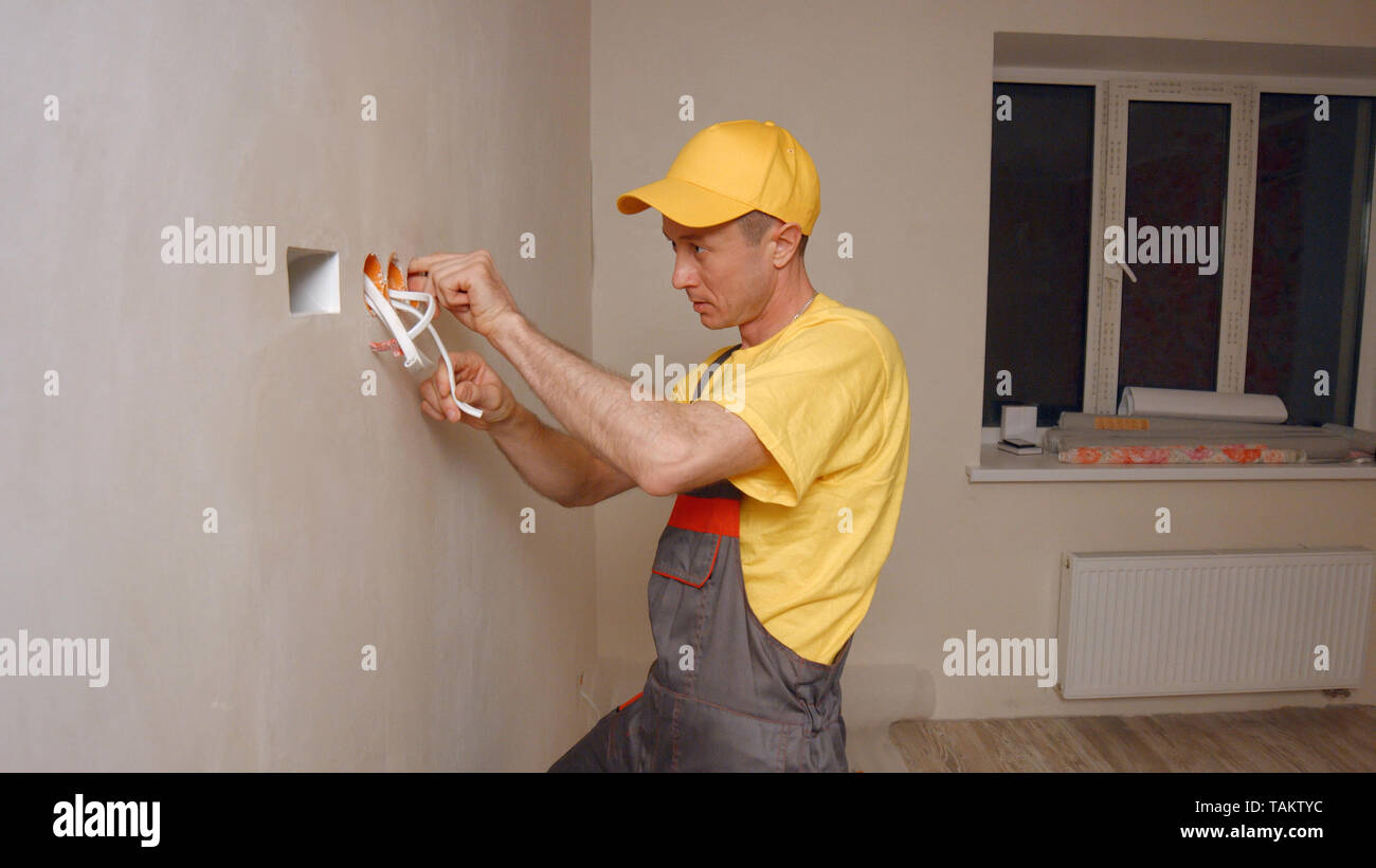 Electrician puts socket. Electrician working with wires in new ...