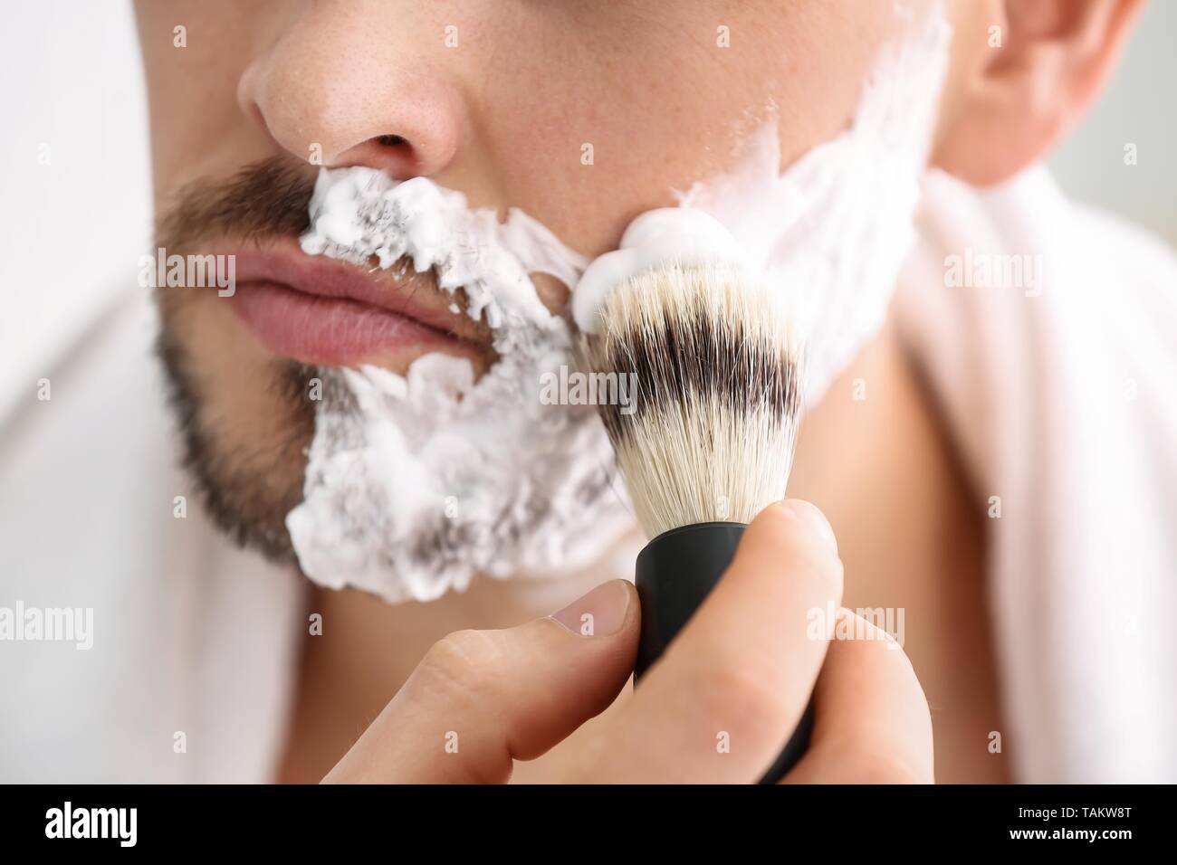 Handsome man applying shaving foam onto his face in bathroom, closeup ...