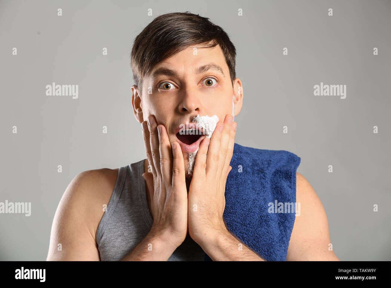 Shocked man having half of his face shaved against grey background ...