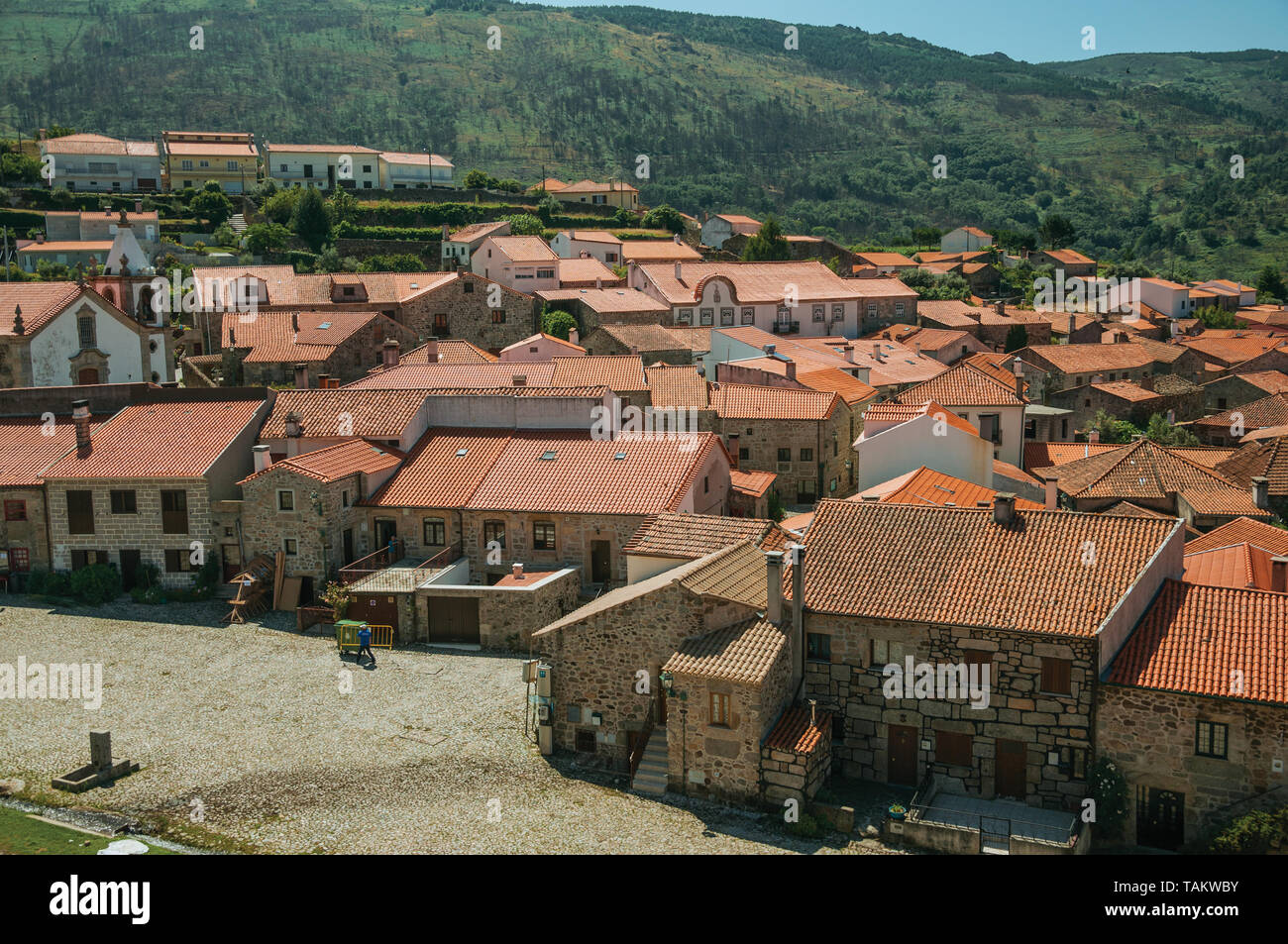 Hilly landscape covered by trees with a square and the roofs of ...