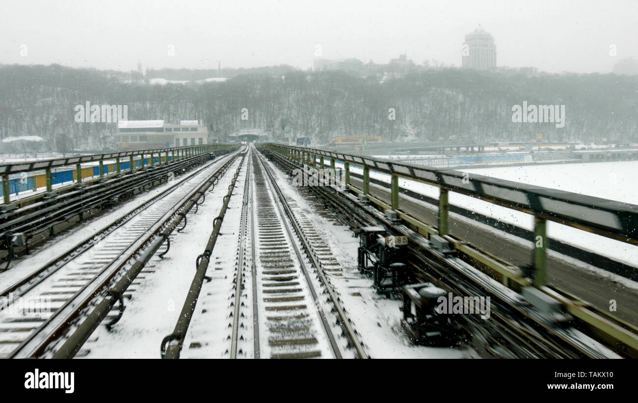 Train moves through the bridge at snow stormy day time. Train moves on ...