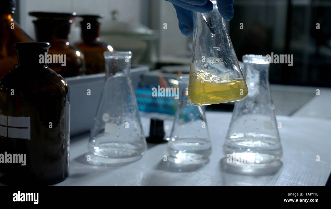 Chemistry laboratory glassware with samples. Hand of chemist or ...