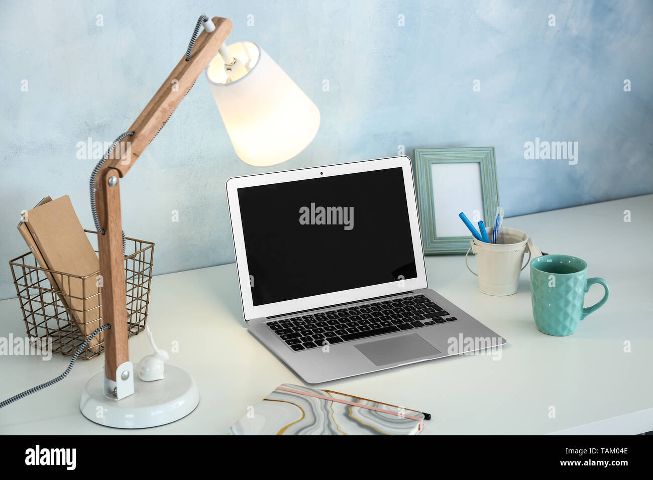 Modern laptop on light table near white color wall Stock Photo - Alamy
