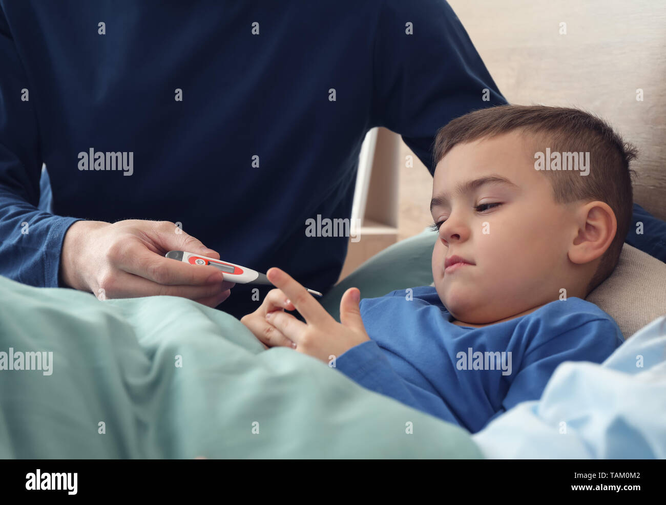 Young father taking care of sick son at home Stock Photo - Alamy
