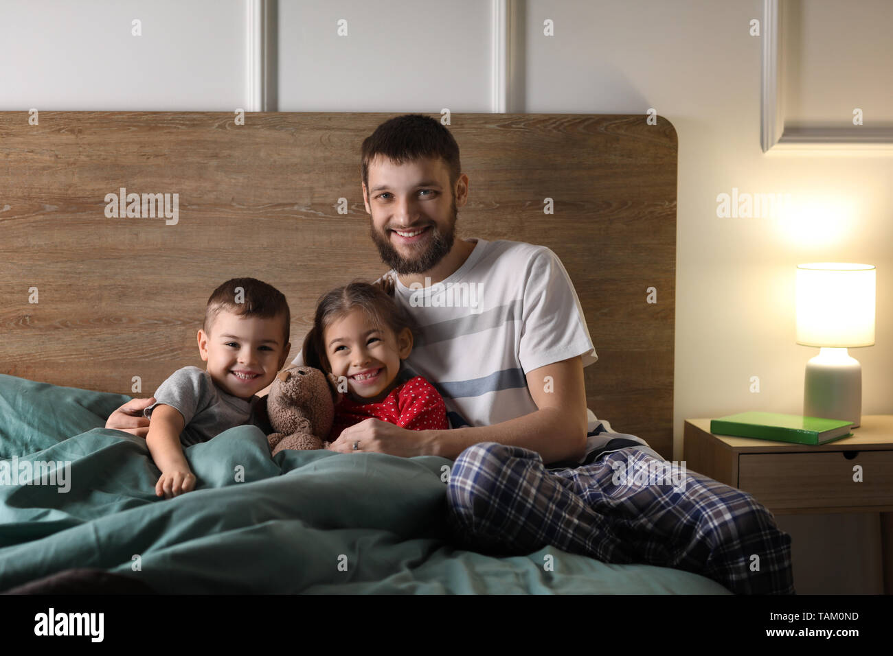 Portrait of happy father with his children in bed at home Stock Photo ...