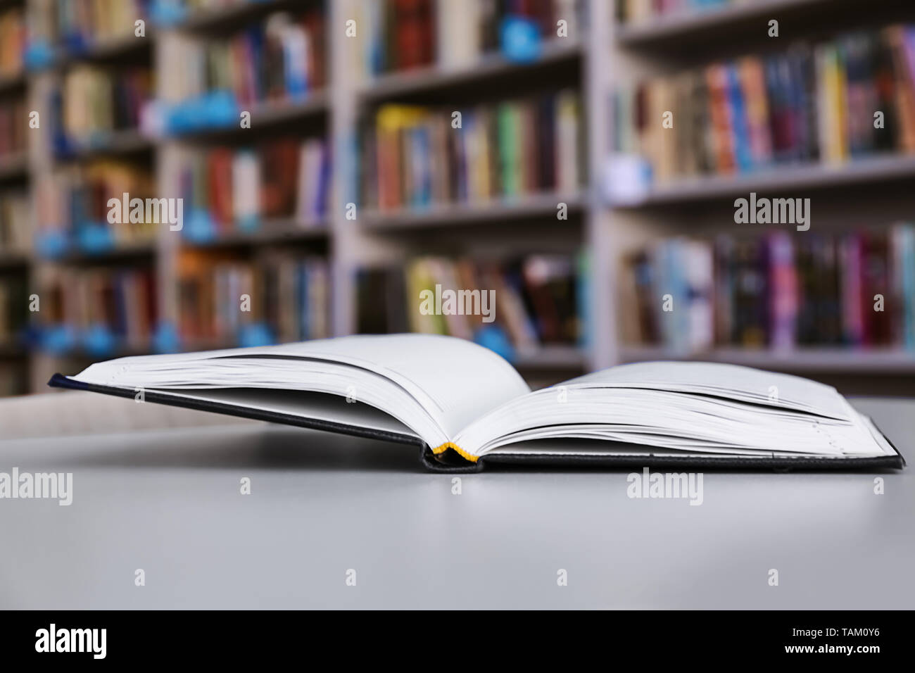 Open book on table in library Stock Photo - Alamy