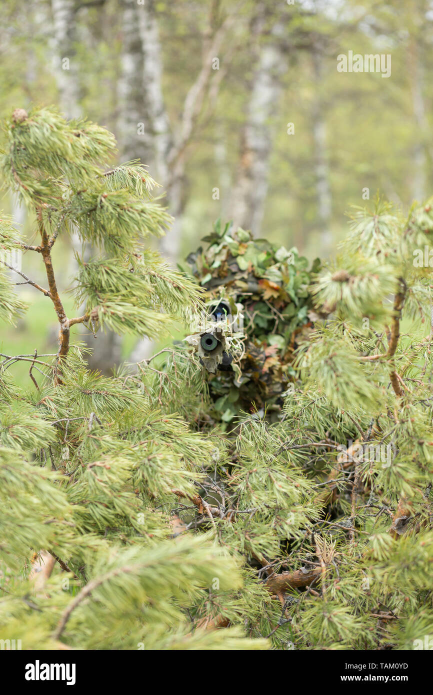 Closeup of young camouflage soldier or sniper holding rifle and shoots ...