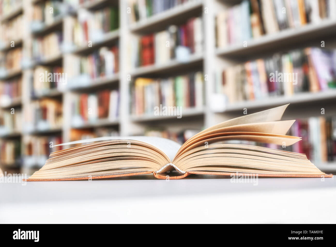 Open book on table in library Stock Photo - Alamy