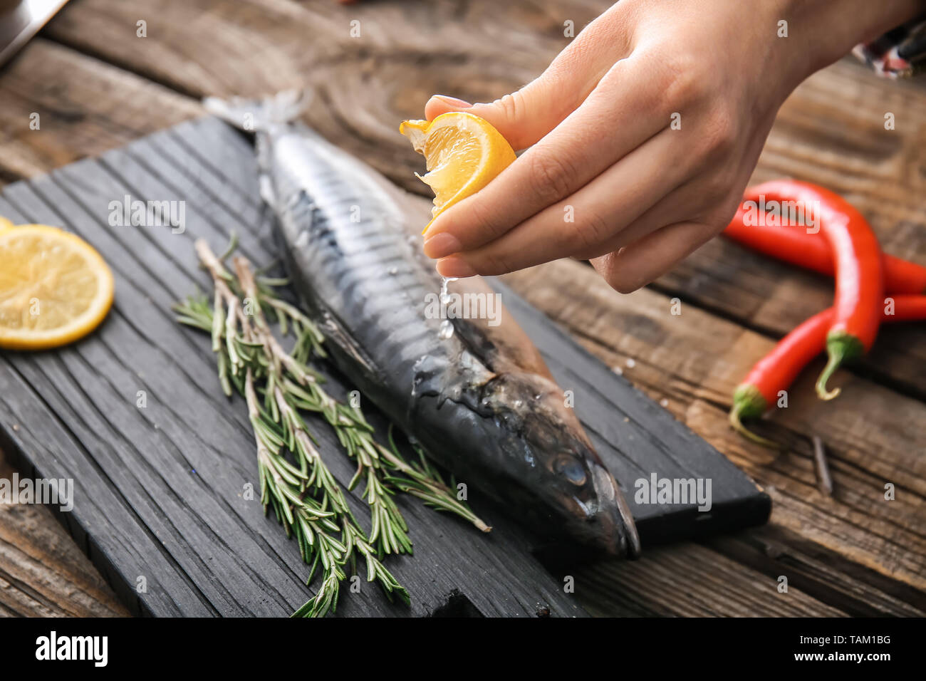 Woman squeezing lemon juice onto tasty mackerel fish, closeup Stock ...