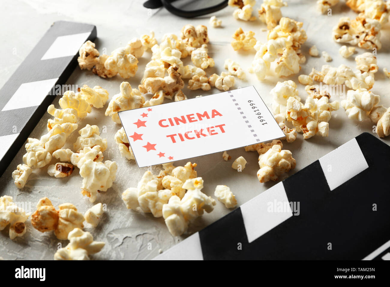 Cinema clapperboard, popcorn and ticket on light background Stock Photo ...
