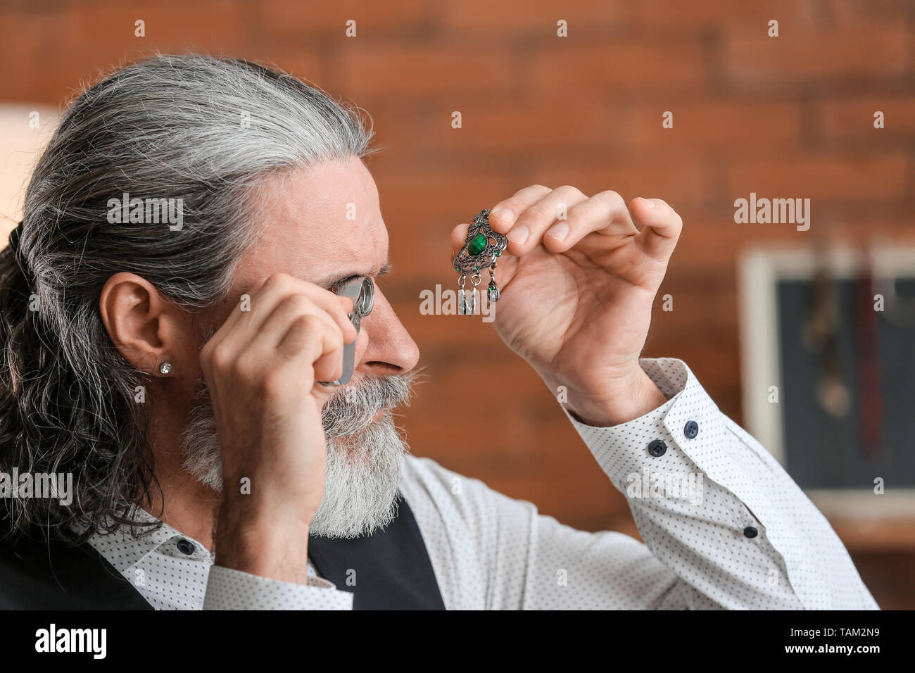 Jeweller with beautiful adornment in workshop Stock Photo - Alamy