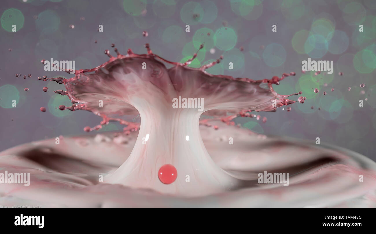 Red drop falling into white liquid, causing amazing unique ripples ...