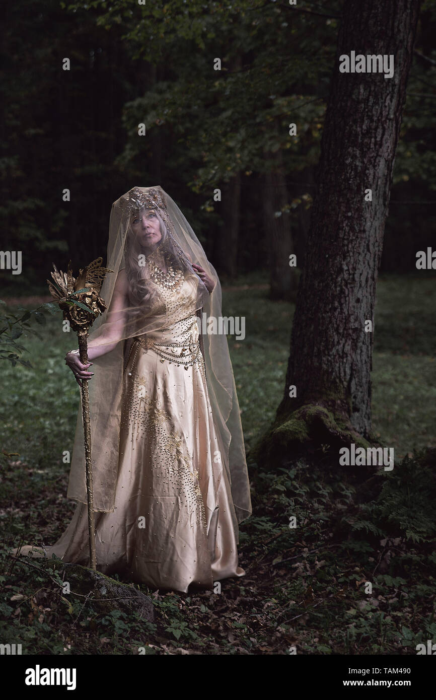 a forest witch in a dark park with a staff in his hands Stock Photo - Alamy