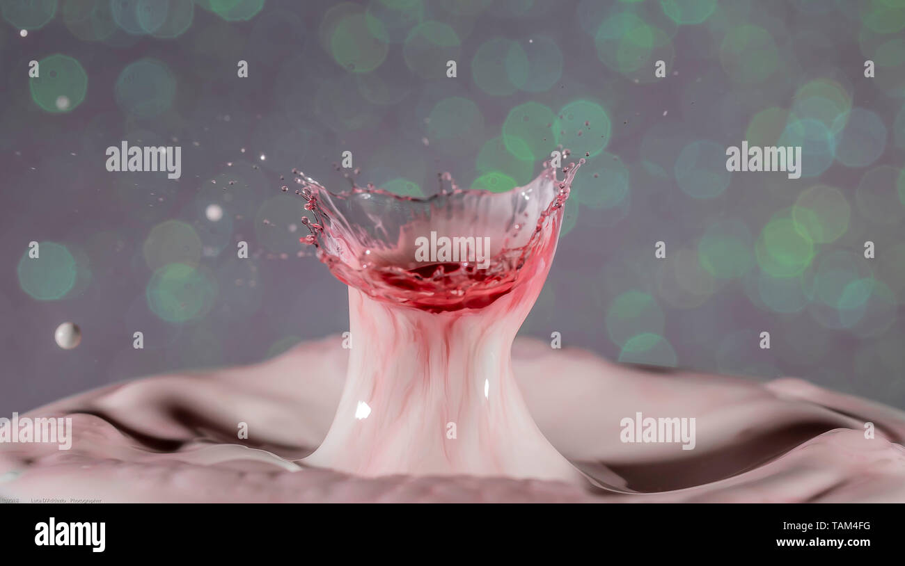 Red drop falling into white liquid, causing amazing unique ripples ...