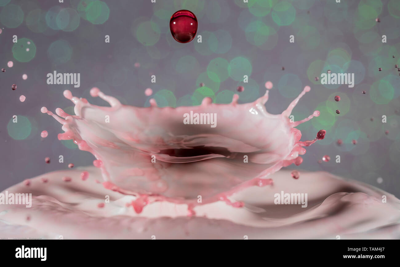 Red drop falling into white liquid, causing amazing unique ripples ...