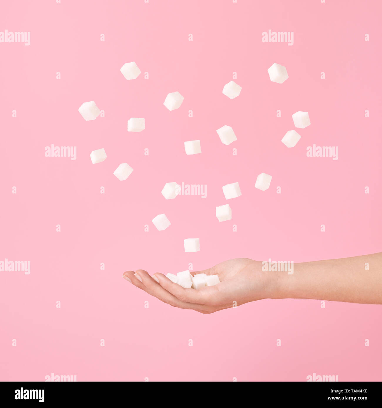 Handful of sugar cubes in hand and flying sugar in heart shape ...