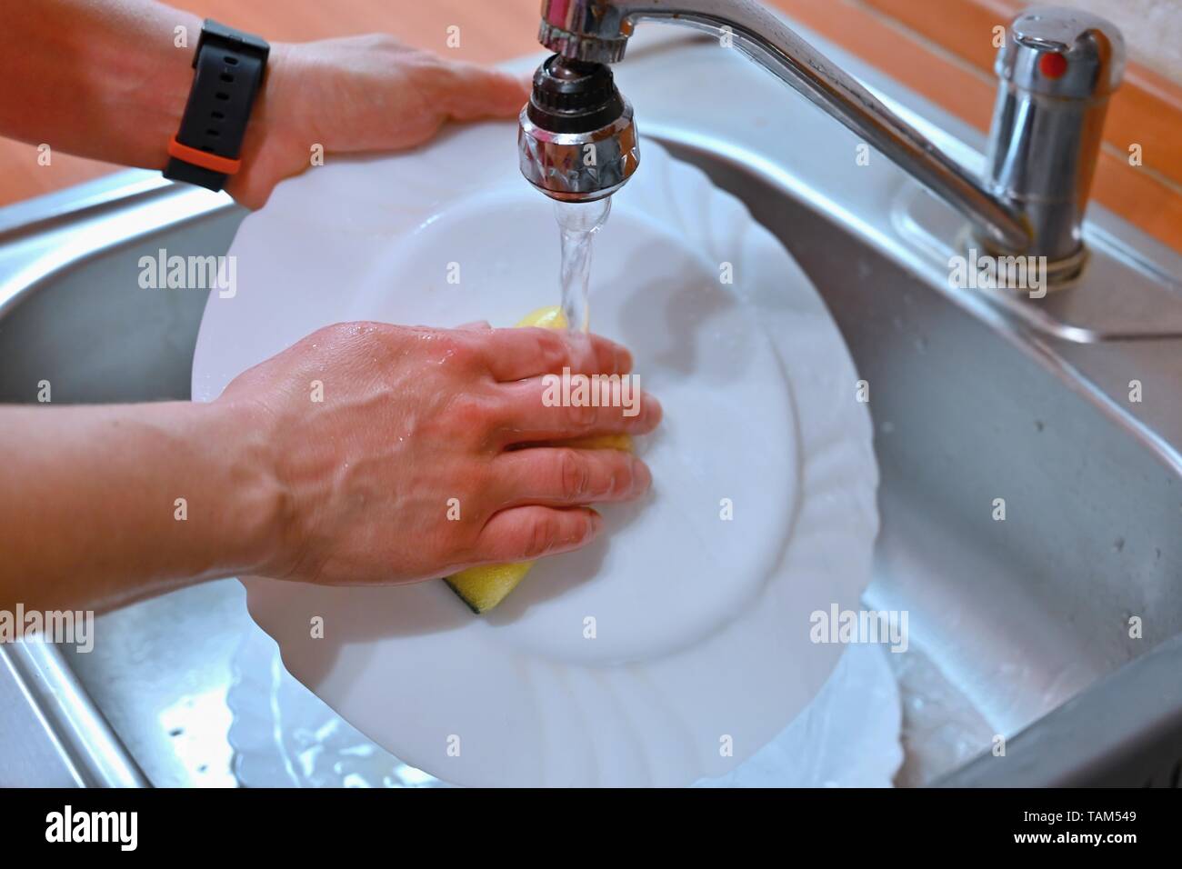 Hand washing dishes. Hand with sponge and sink in kitchen washing dirty ...