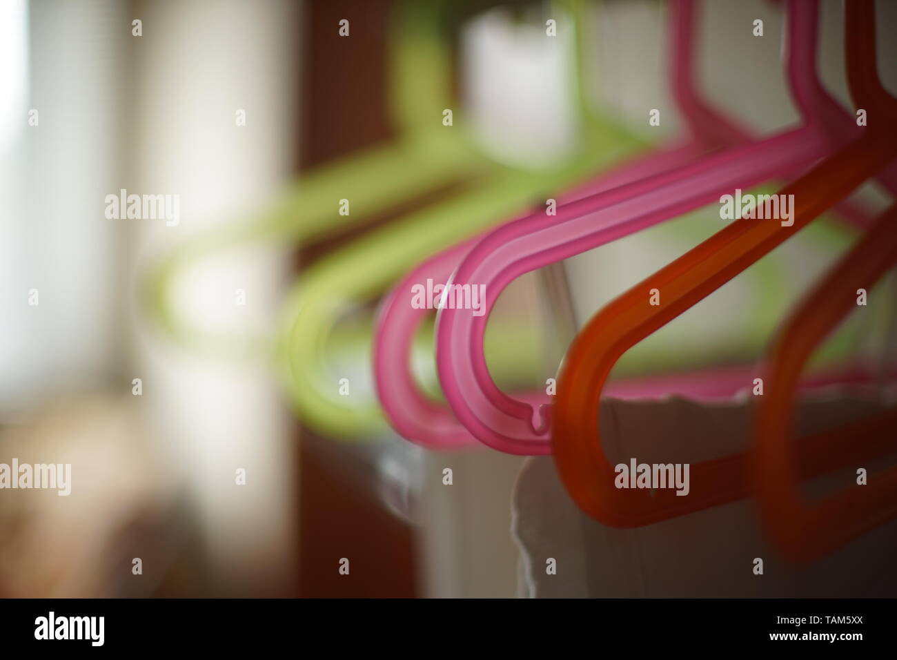 A set of colorful plastic hangers hanging on the rack Stock Photo - Alamy