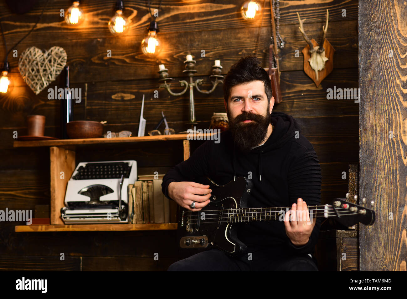 Man bearded musician enjoy evening with bass guitar, wooden background ...
