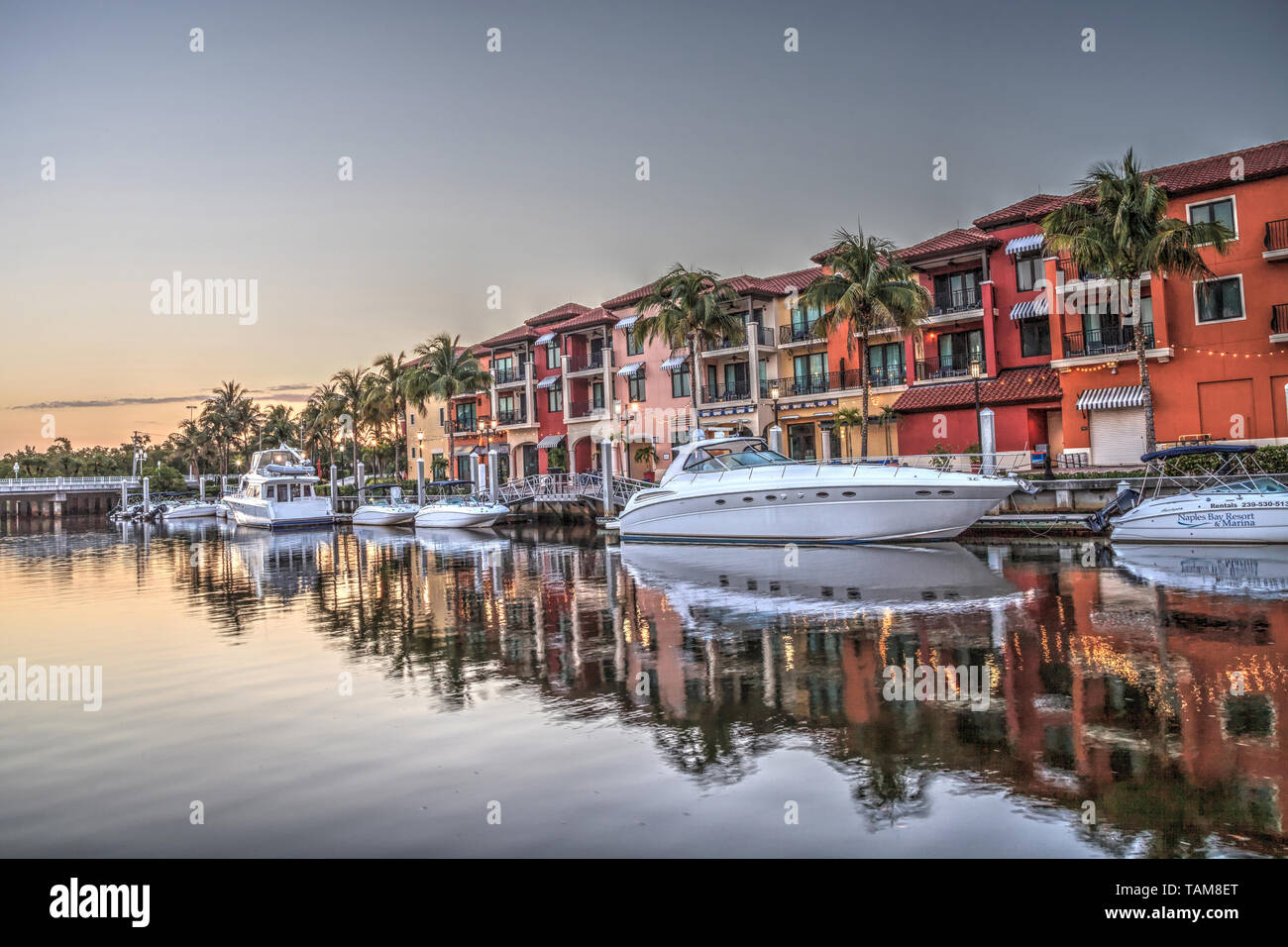 Sunrise over a harbor with sailboats and colorful buildings in Naples ...