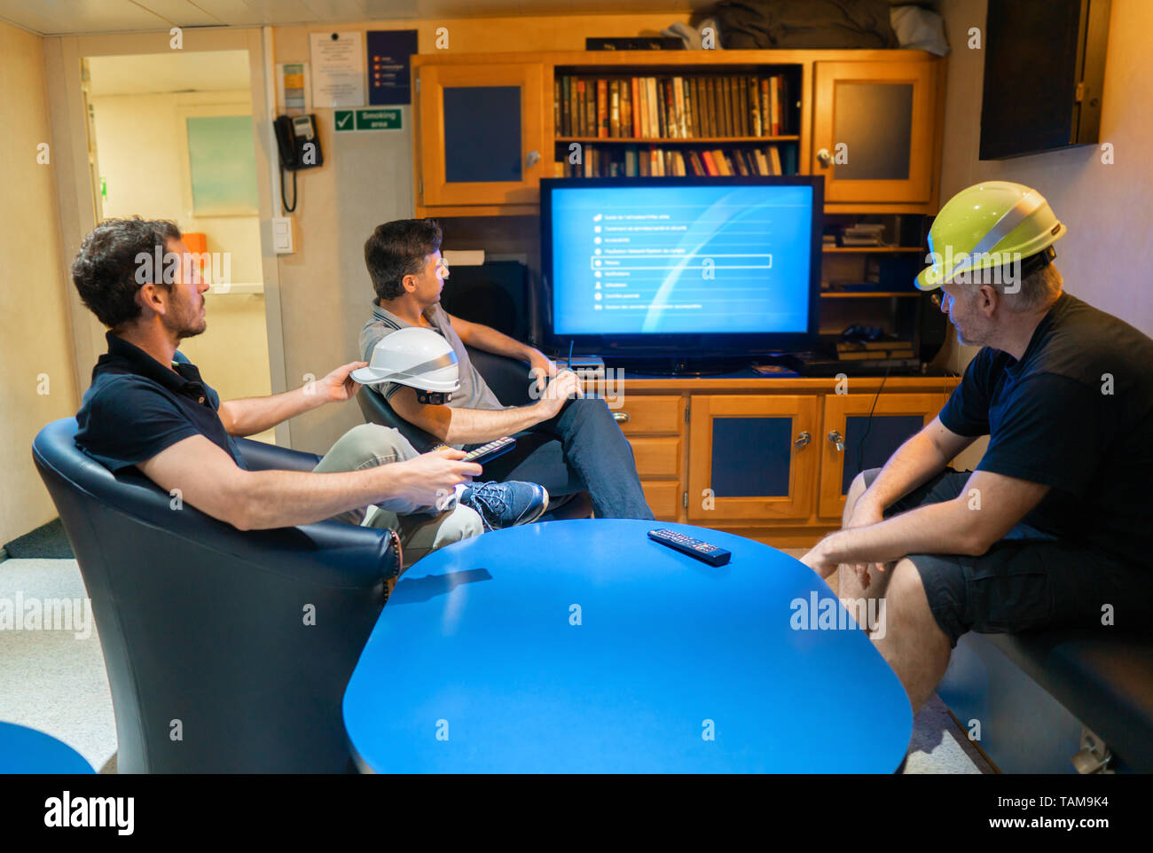 Happy team of ship officers watch TV onboard of vessel Stock Photo - Alamy