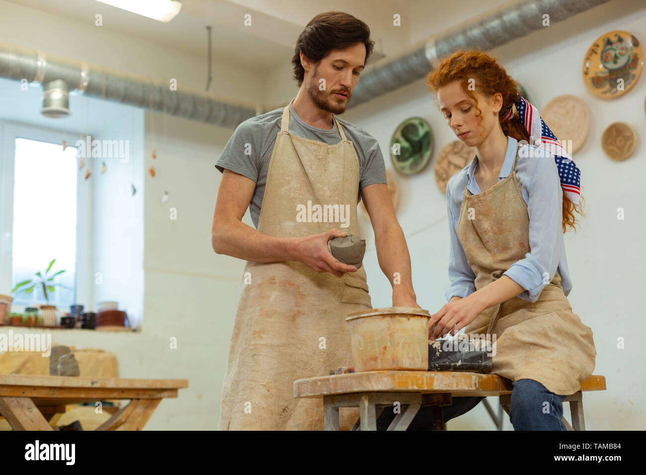Master presenting clay. Concentrated professional couple working in ...