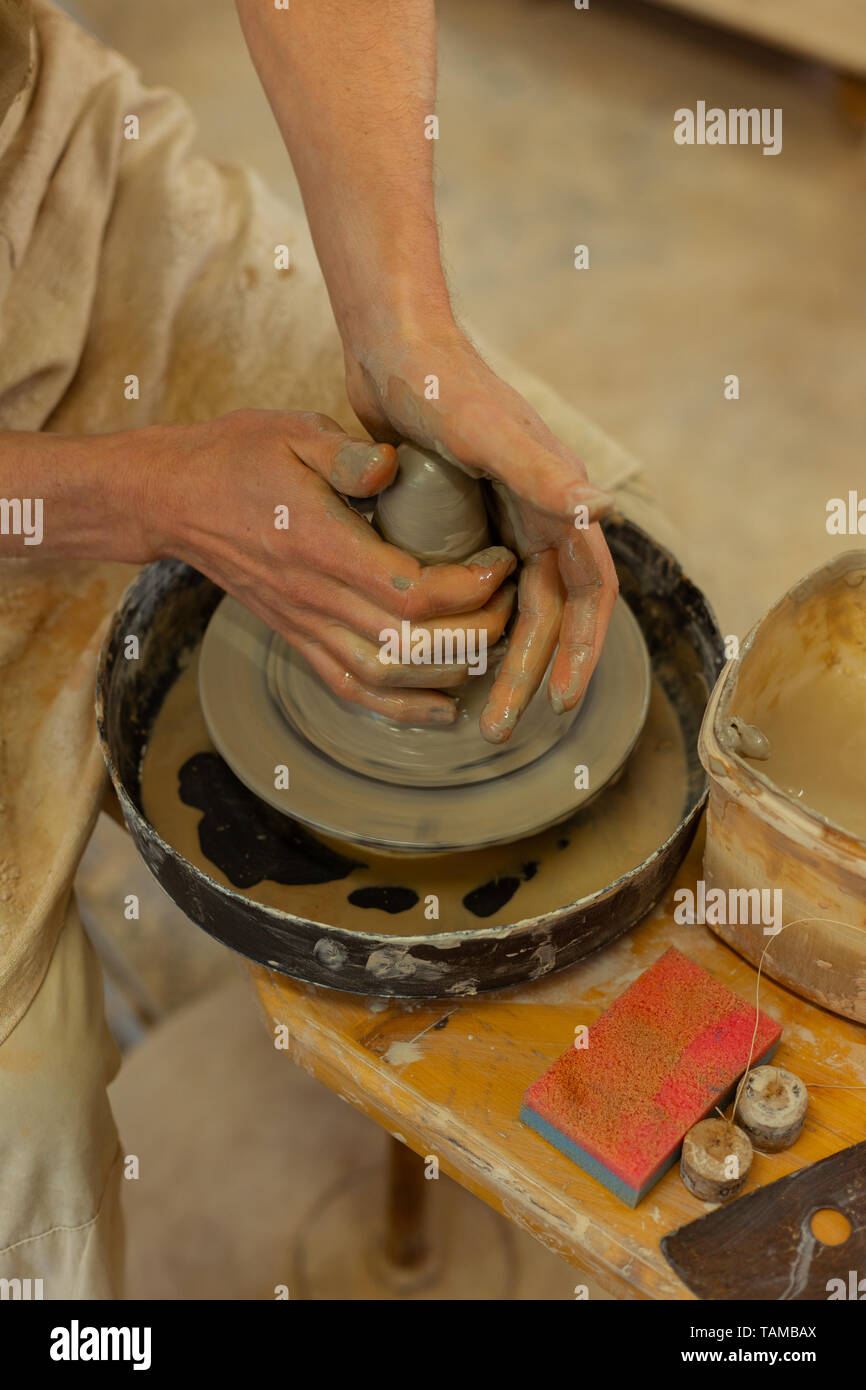 Forming new creation. Accurate professional pottery master using wheel ...