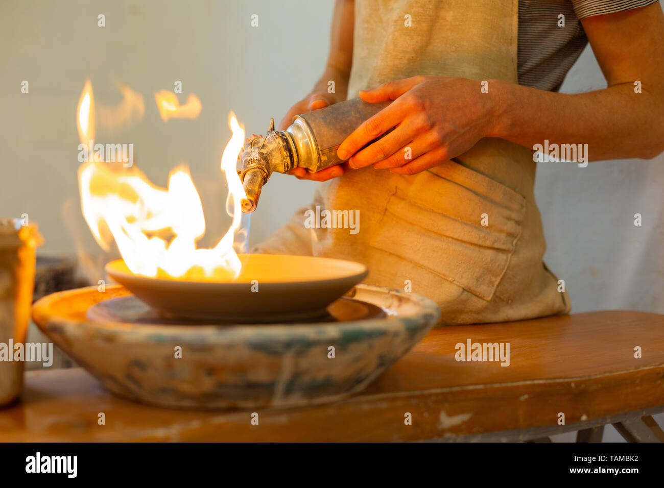 Step in manufacturing. Confident skilled man setting clay plate on fire ...