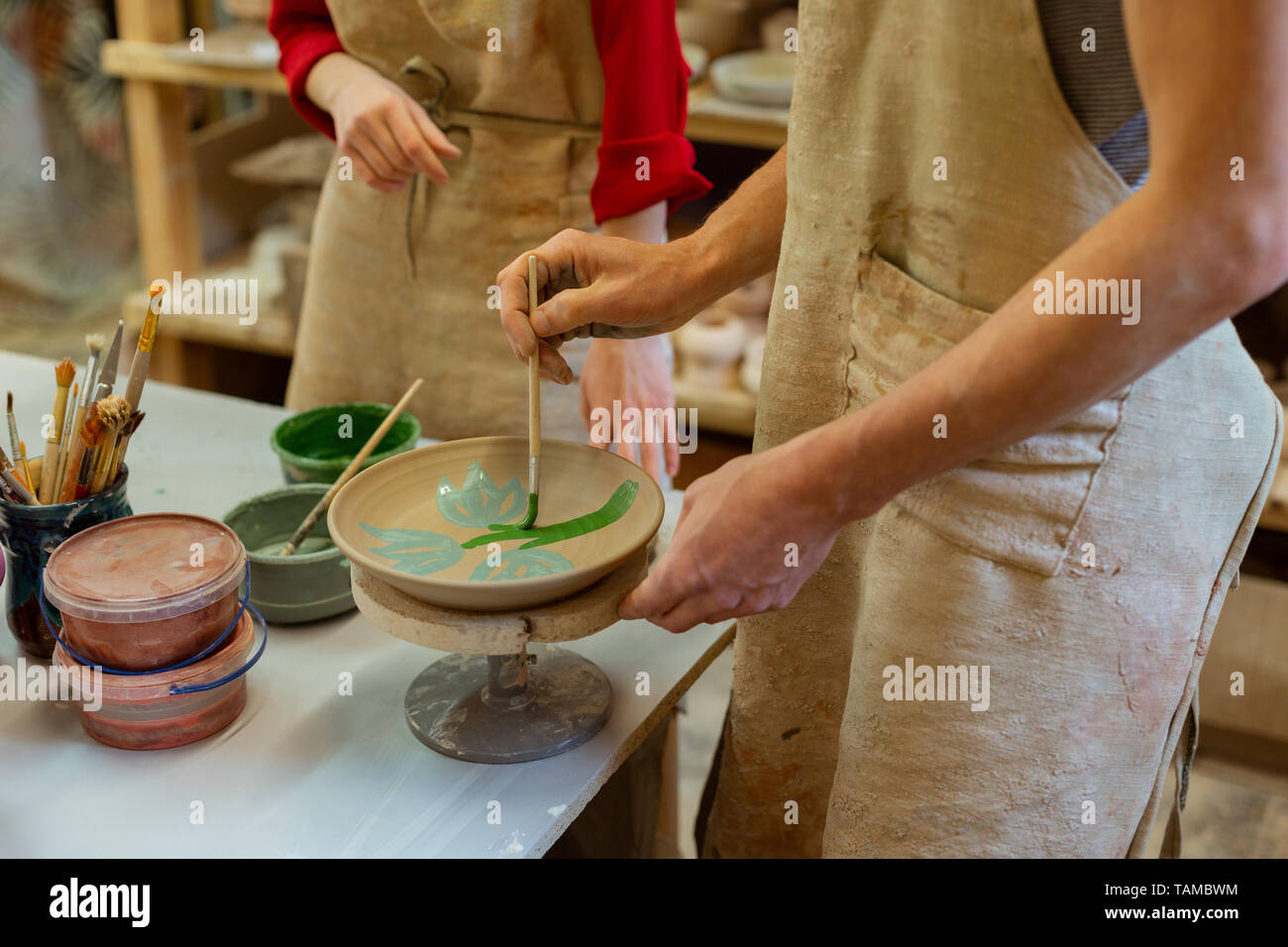 Colorful paintings. Focused interested pottery master finishing ...