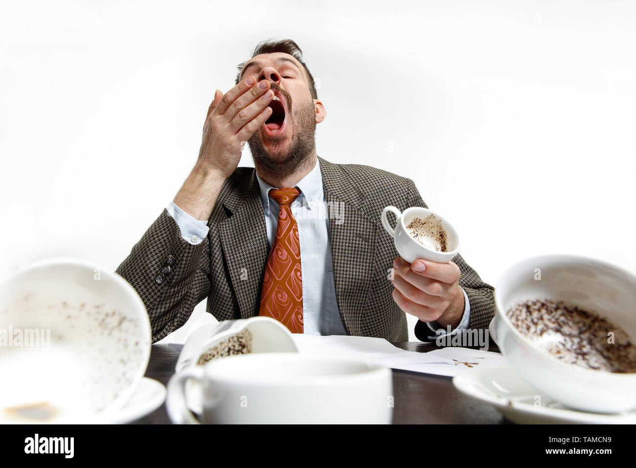 Has no time for resting. Young man drinking a lot of coffee, but can't ...