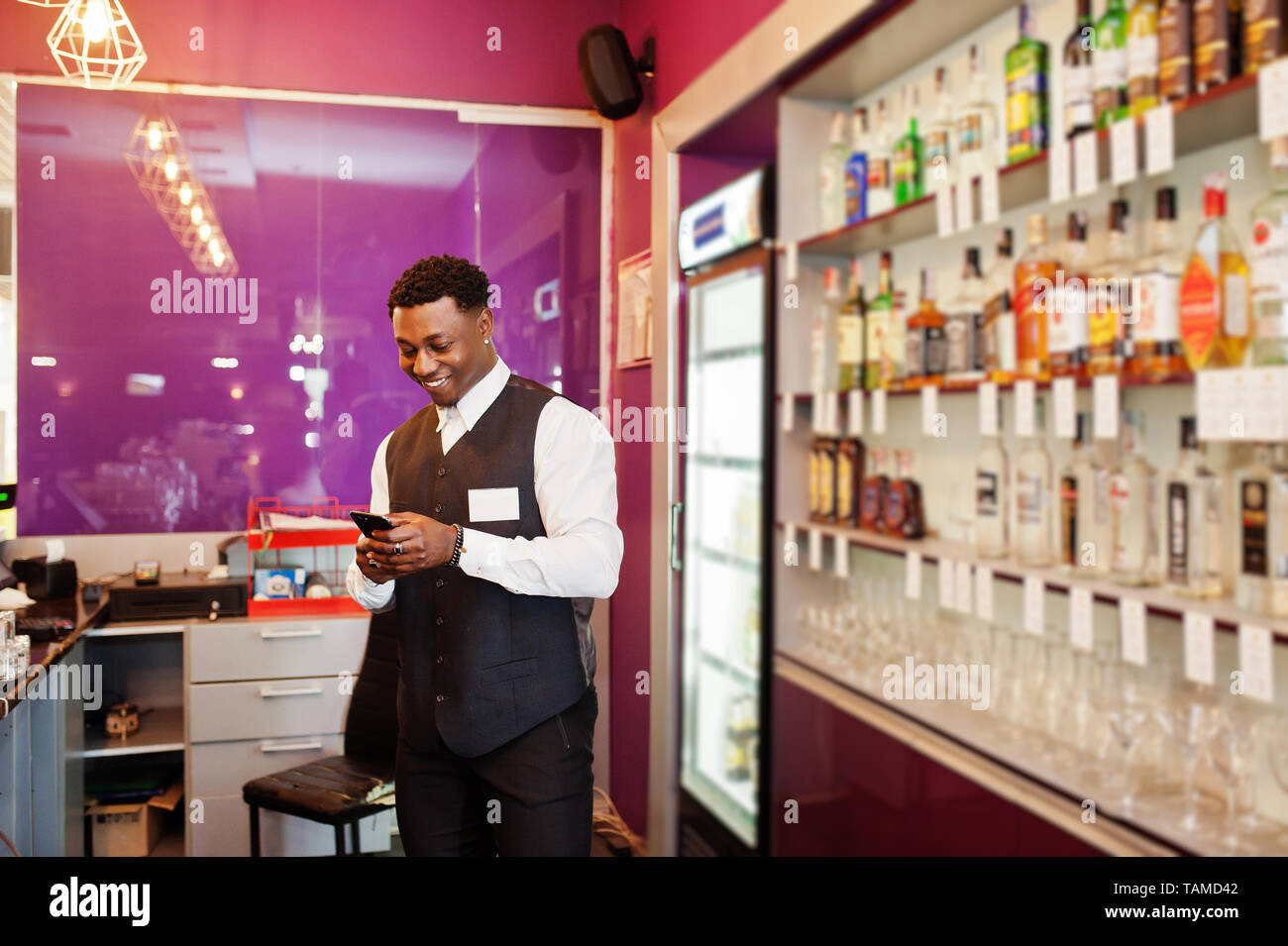 African american bartender at bar with mobile phone at hands Stock ...