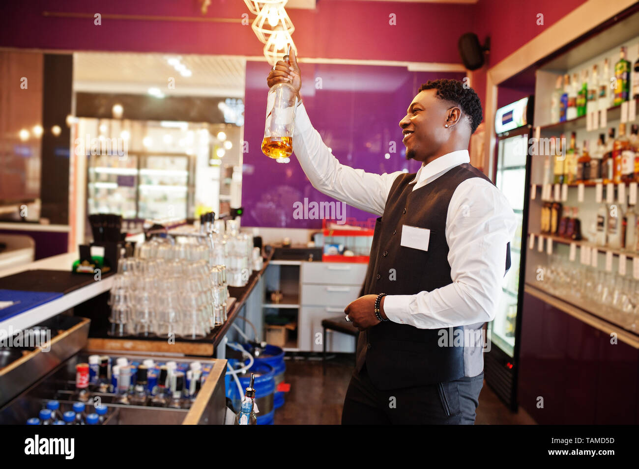 African american bartender at bar holding bootle. Alcoholic beverage ...