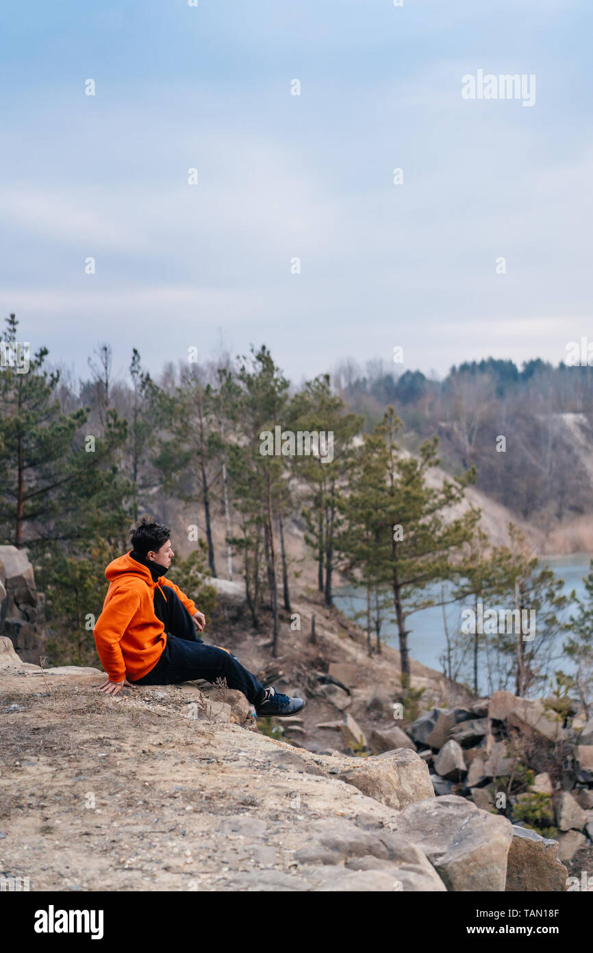A young man sitting on the edge of a cliff poses for the camera Stock ...