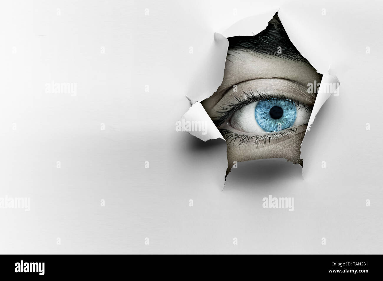 Eye in a hole of torn paper Stock Photo - Alamy