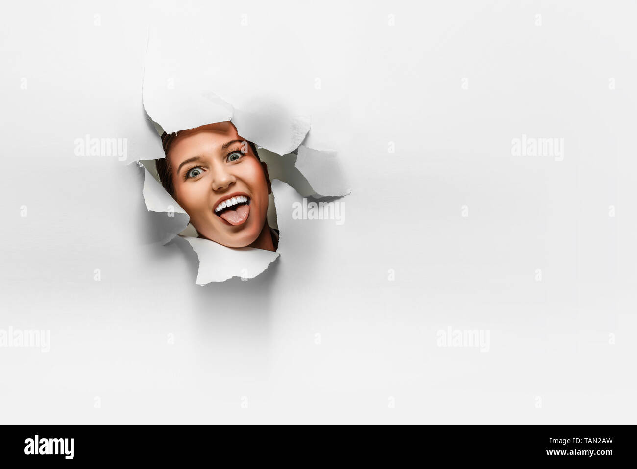 Woman looking out from a hole of torn paper Stock Photo - Alamy