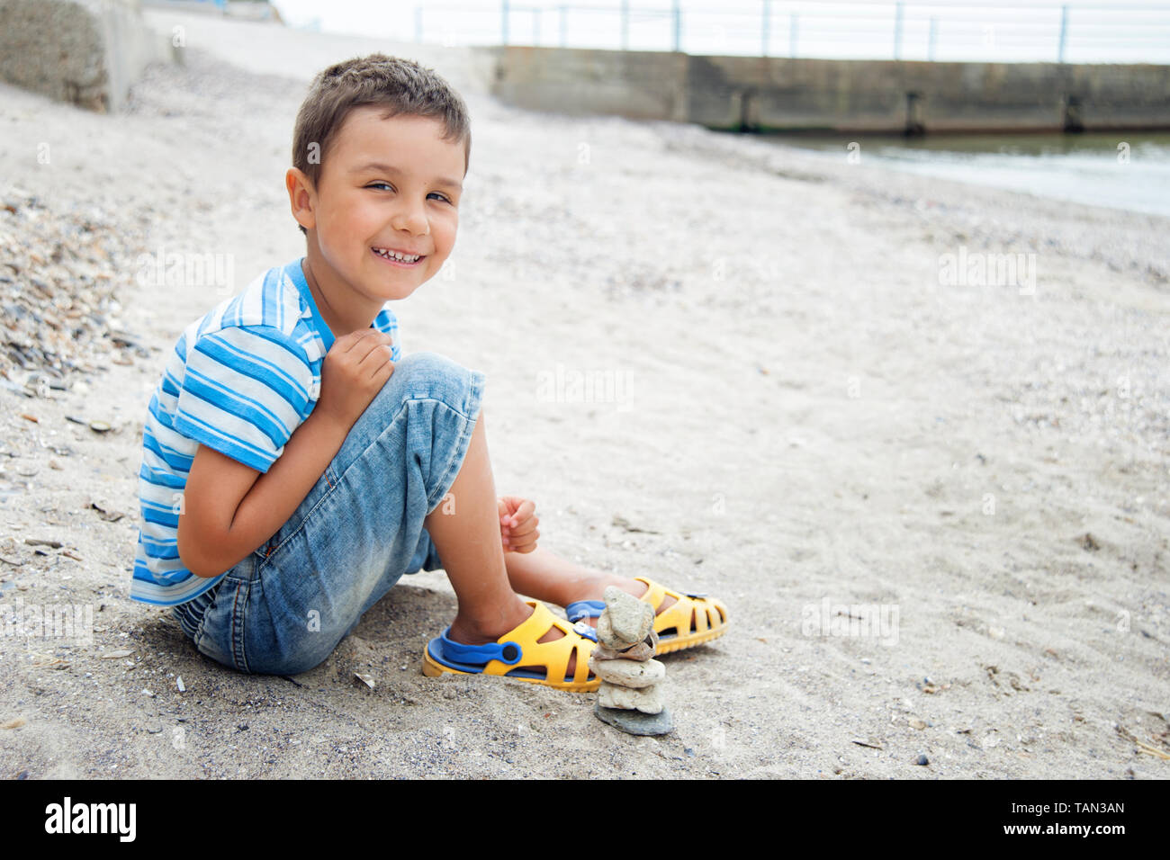 the little boy by the sea collects seashells on the beach. sunset ...