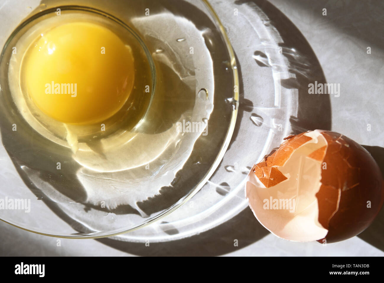 Broken raw chicken egg in the glass saucer and the its brown shell in ...