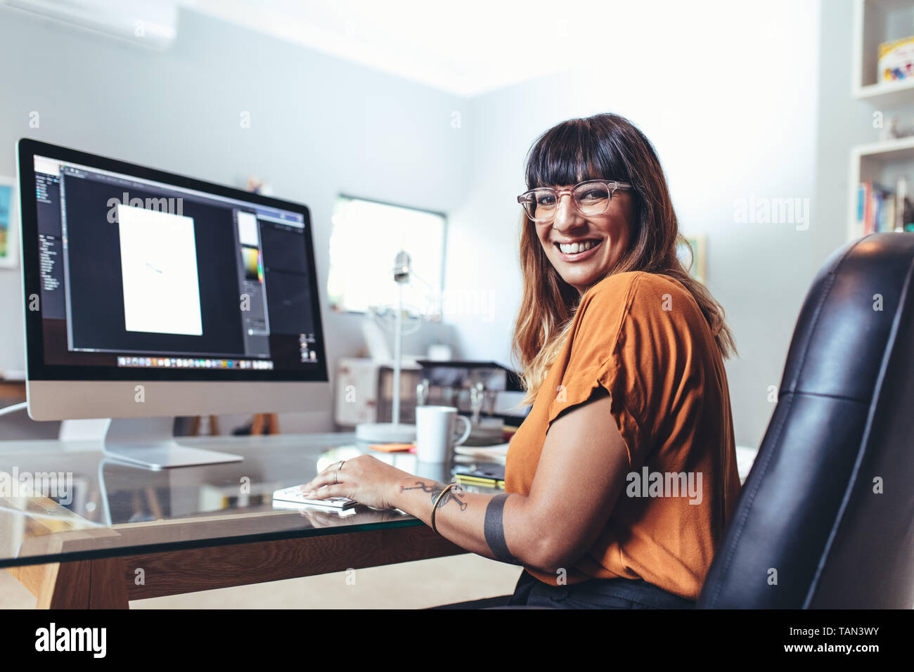 Cheerful female illustrator working on computer. Smiling artist working ...